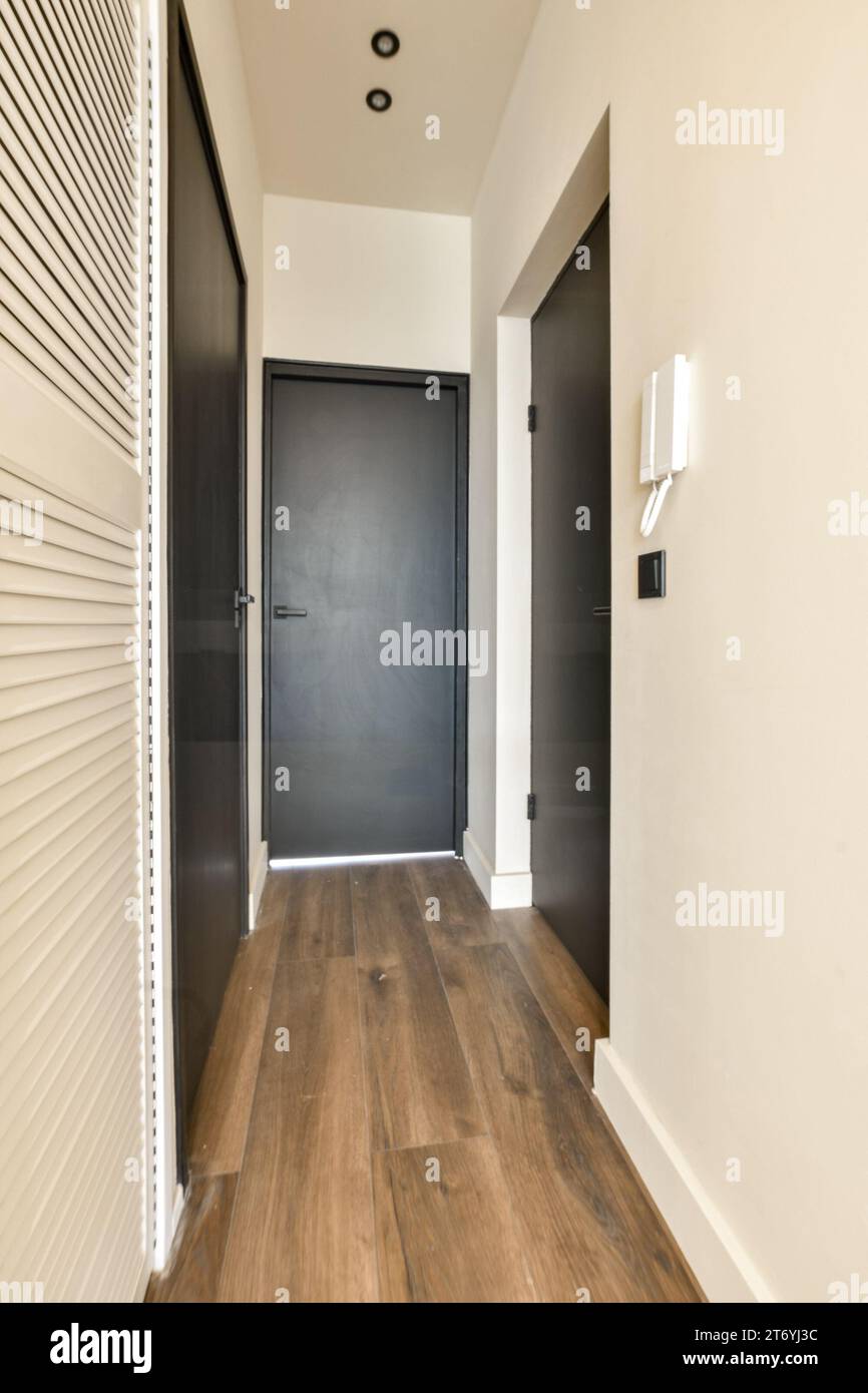 an empty hallway with wood flooring and black shutters on the door to ...