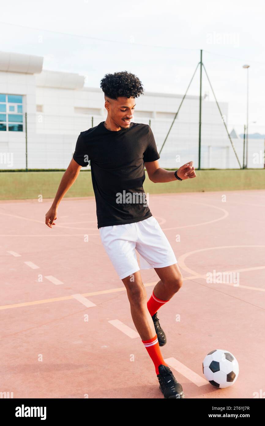 Black football player running kicking ball sports ground Stock Photo ...