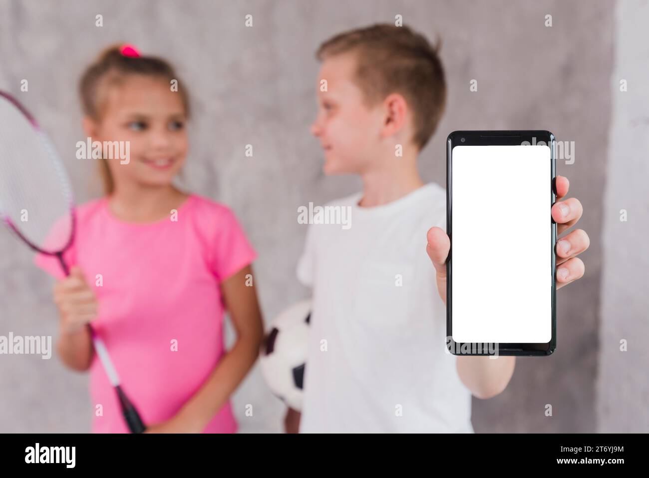 Boy standing with girl showing mobile phone with white screen display ...