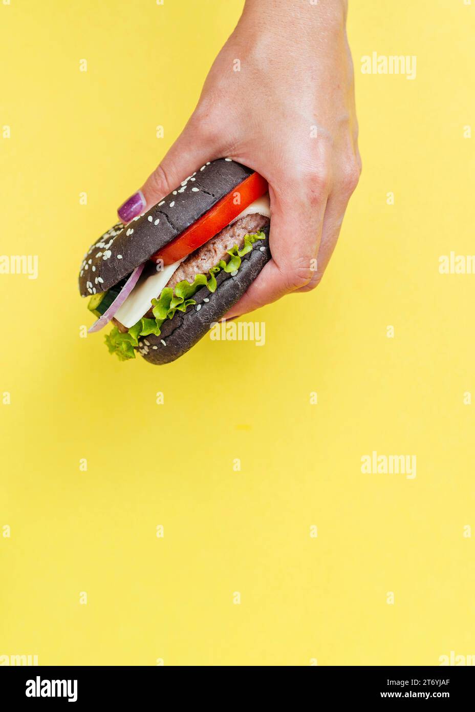 Burger held front yellow background Stock Photo - Alamy
