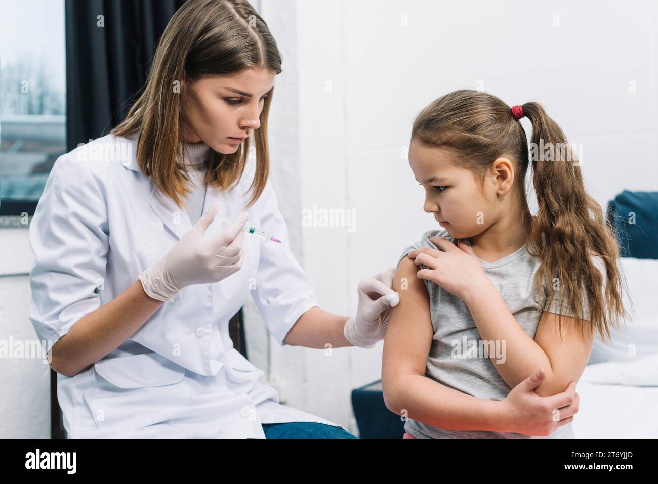 Close up female doctor wearing white gloves hand giving syringe patient ...