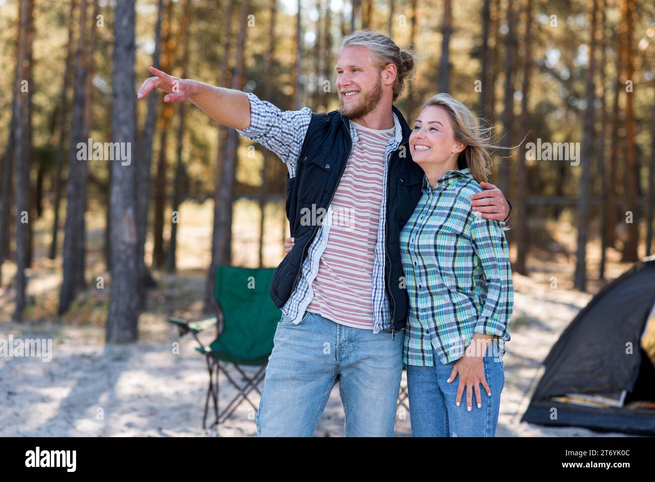Couple hugging man pointing his finger Stock Photo - Alamy