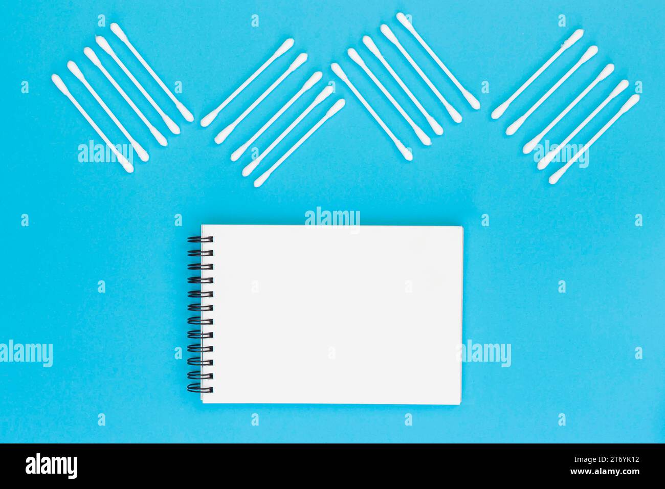 Design made with cotton swabs blank spiral notepad blue background ...