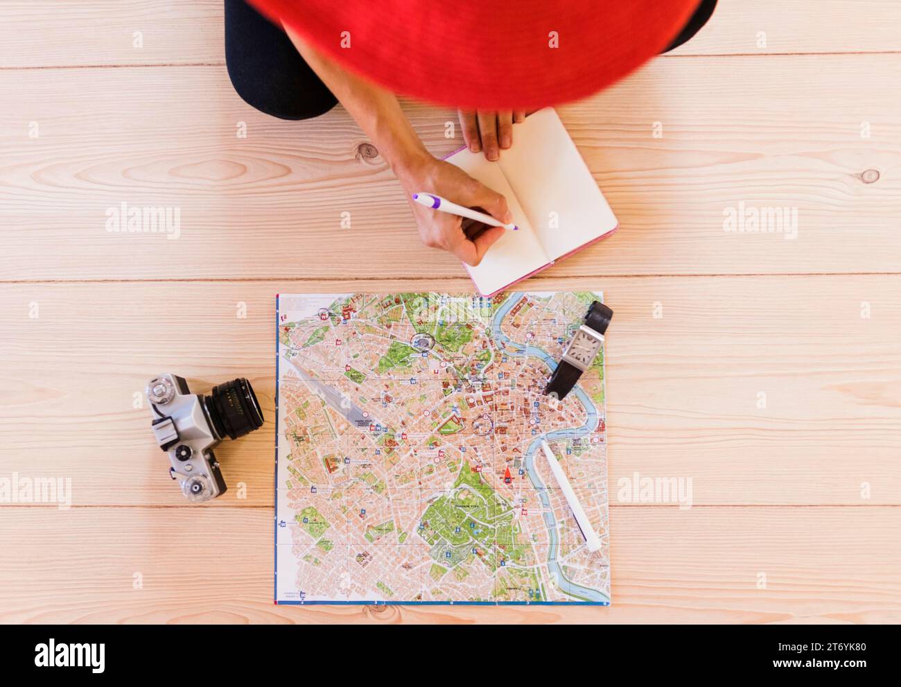 Elevated view person writing diary with map wrist watch camera wooden ...
