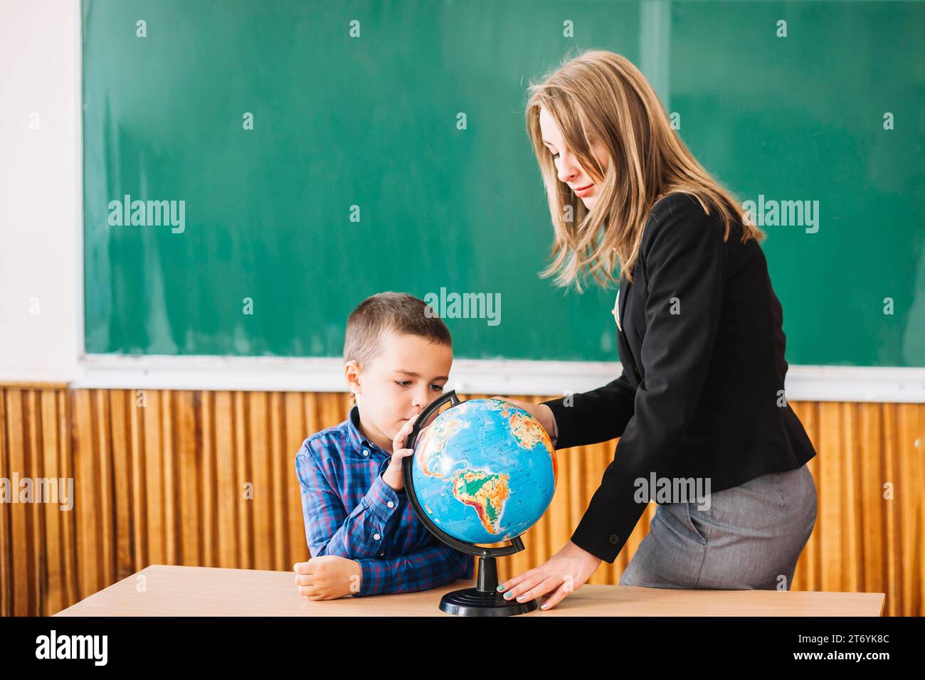 Female teacher student boy working with globe Stock Photo - Alamy