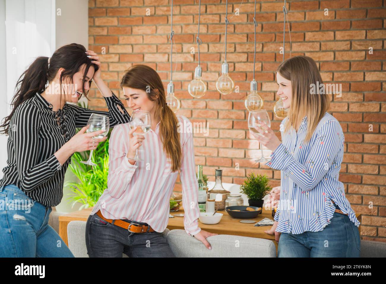 Female friends laughing bricks room Stock Photo - Alamy