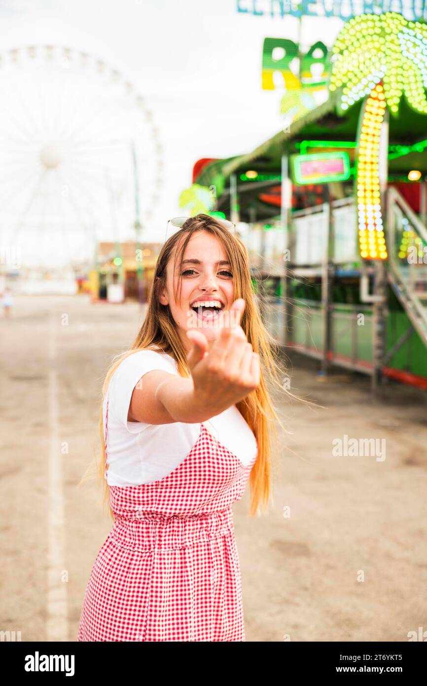 Happy young woman inviting someone with one hand amusement park Stock ...