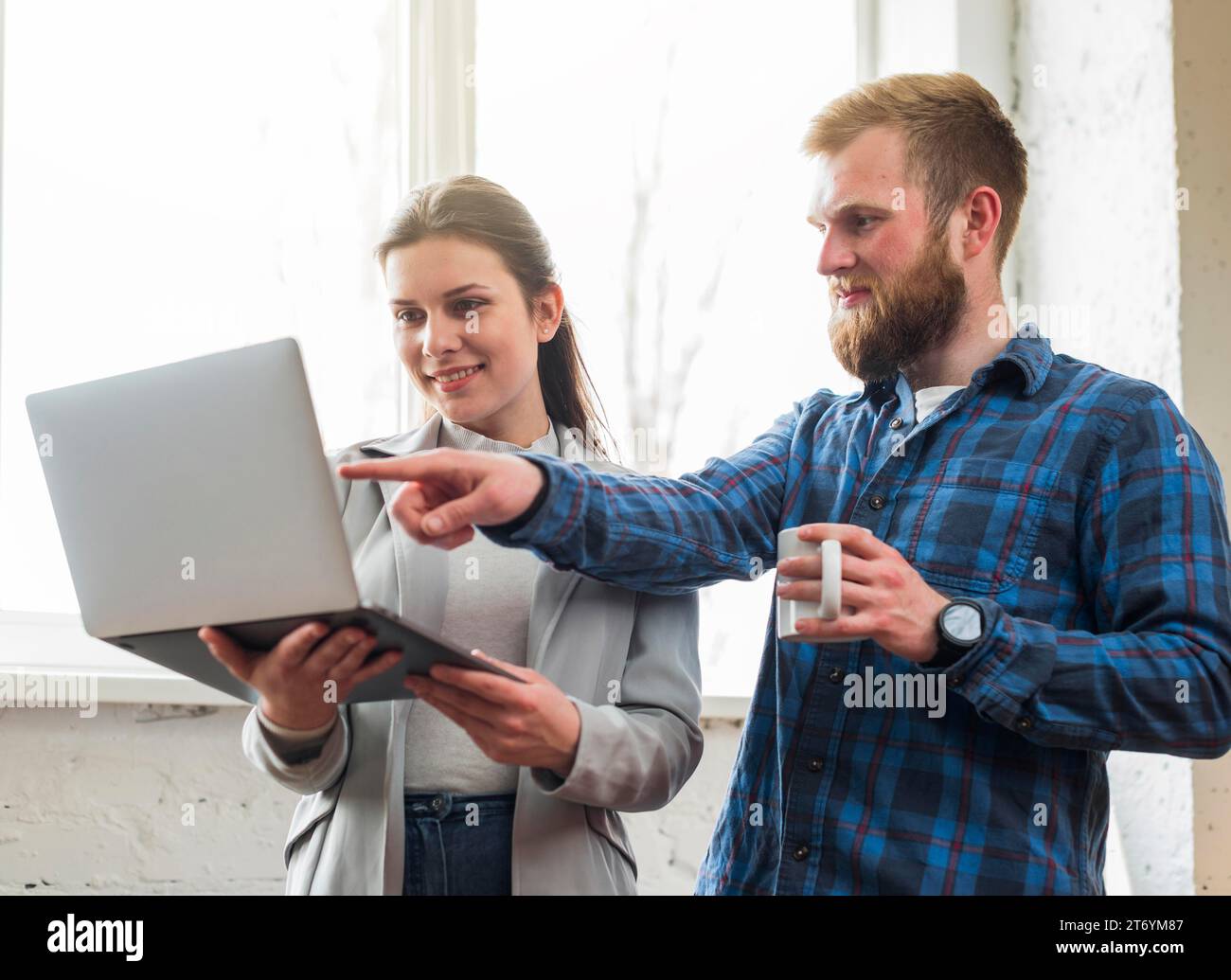 Man pointing laptop hold by his female colleague Stock Photo - Alamy