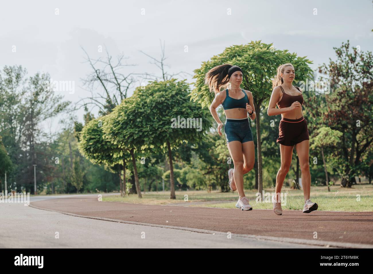 Two fit women jogging in nature, surrounded by greenery. Inspiring ...