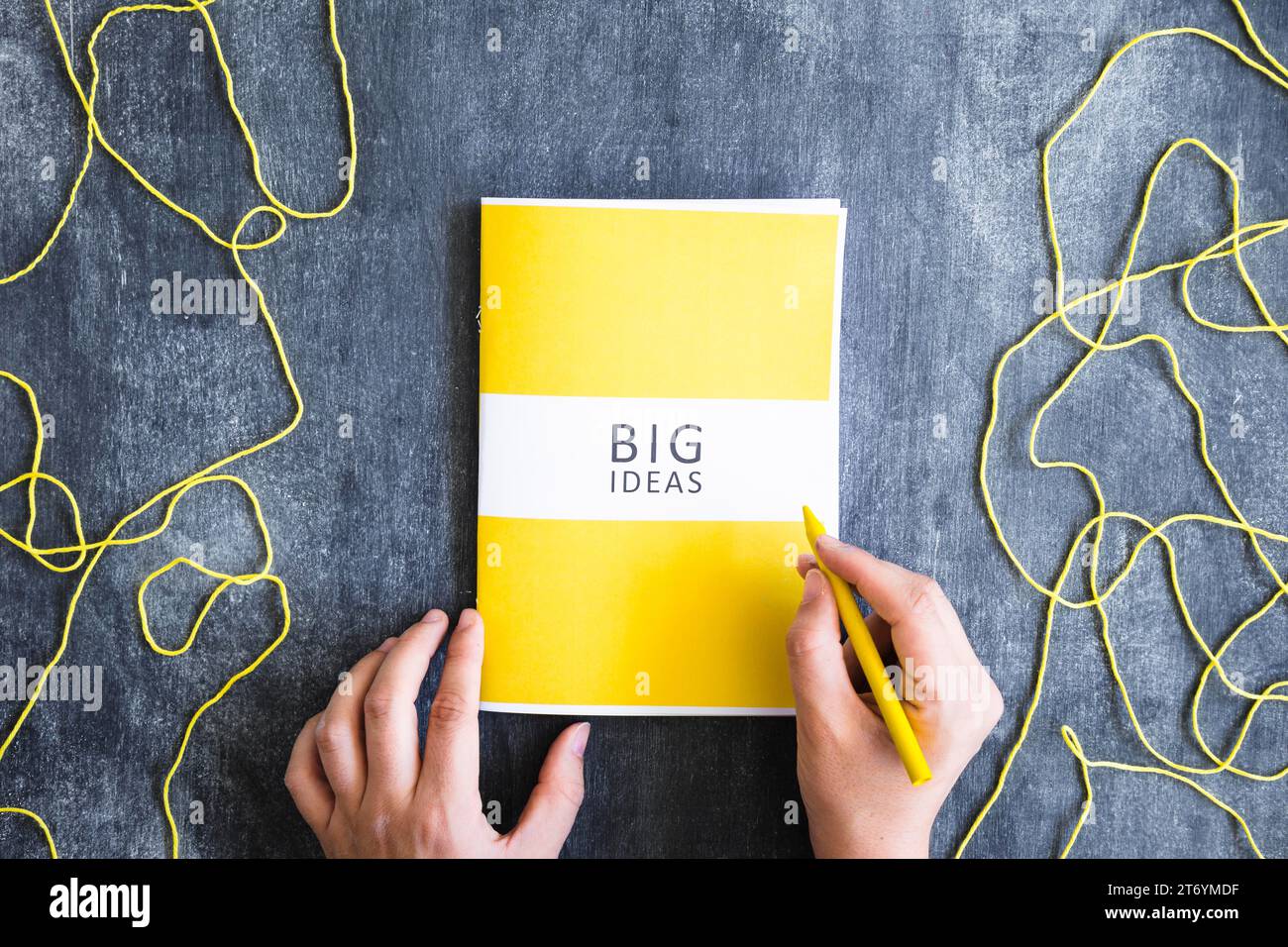 Overhead view person writing big ideas with yellow crayons chalkboard ...