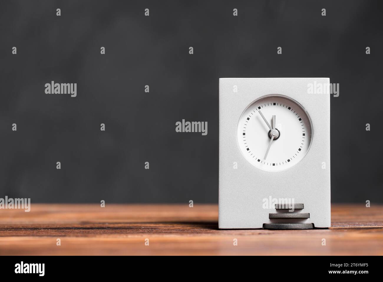 Modern rectangular clock textured wooden desk against black background ...