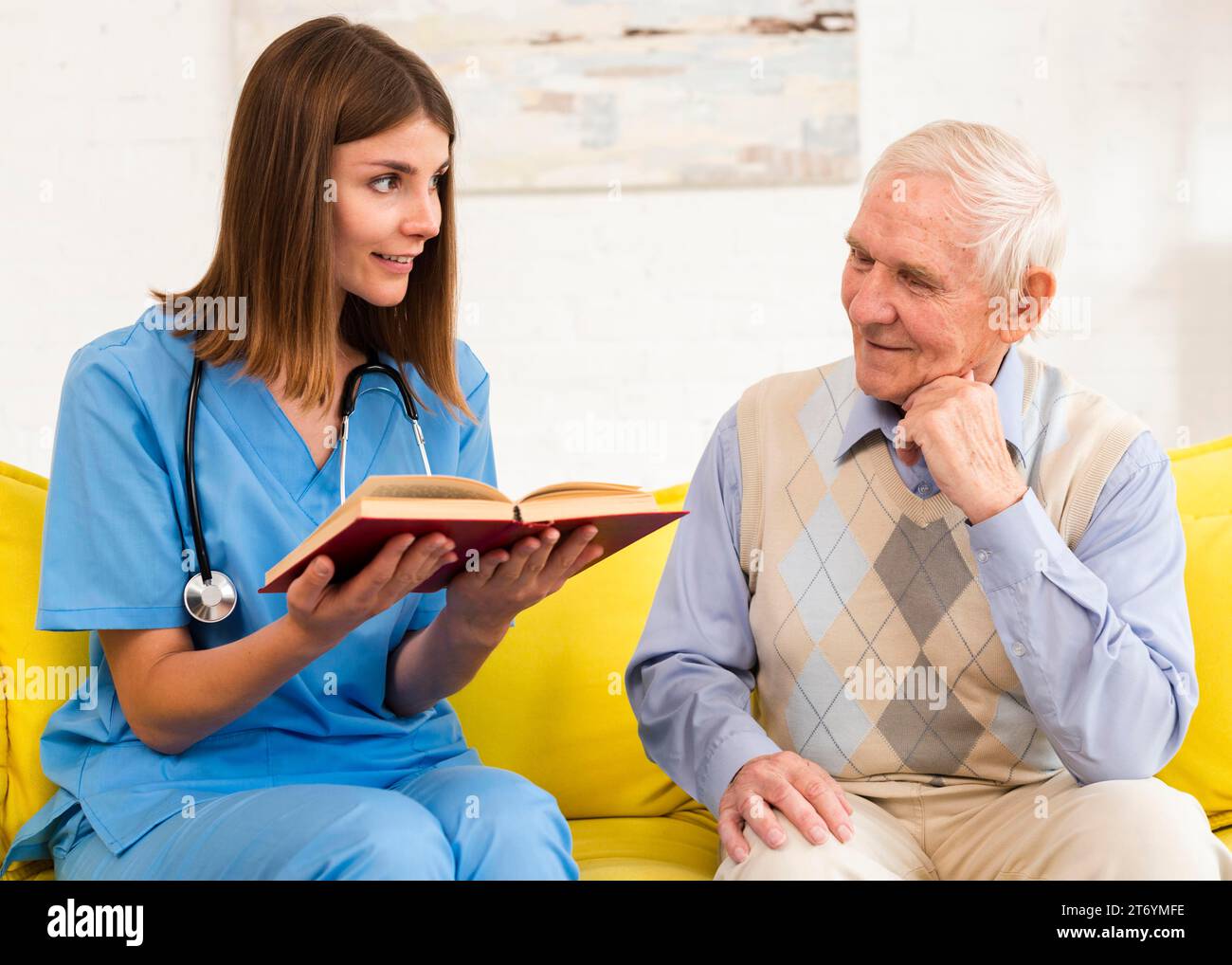 Nurse reading book old man Stock Photo - Alamy