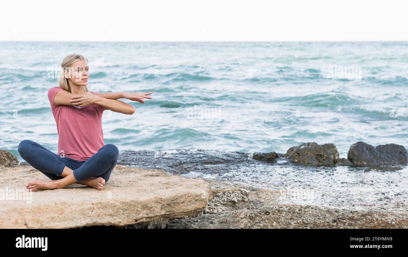 Pretty blonde woman stretching beach Stock Photo - Alamy