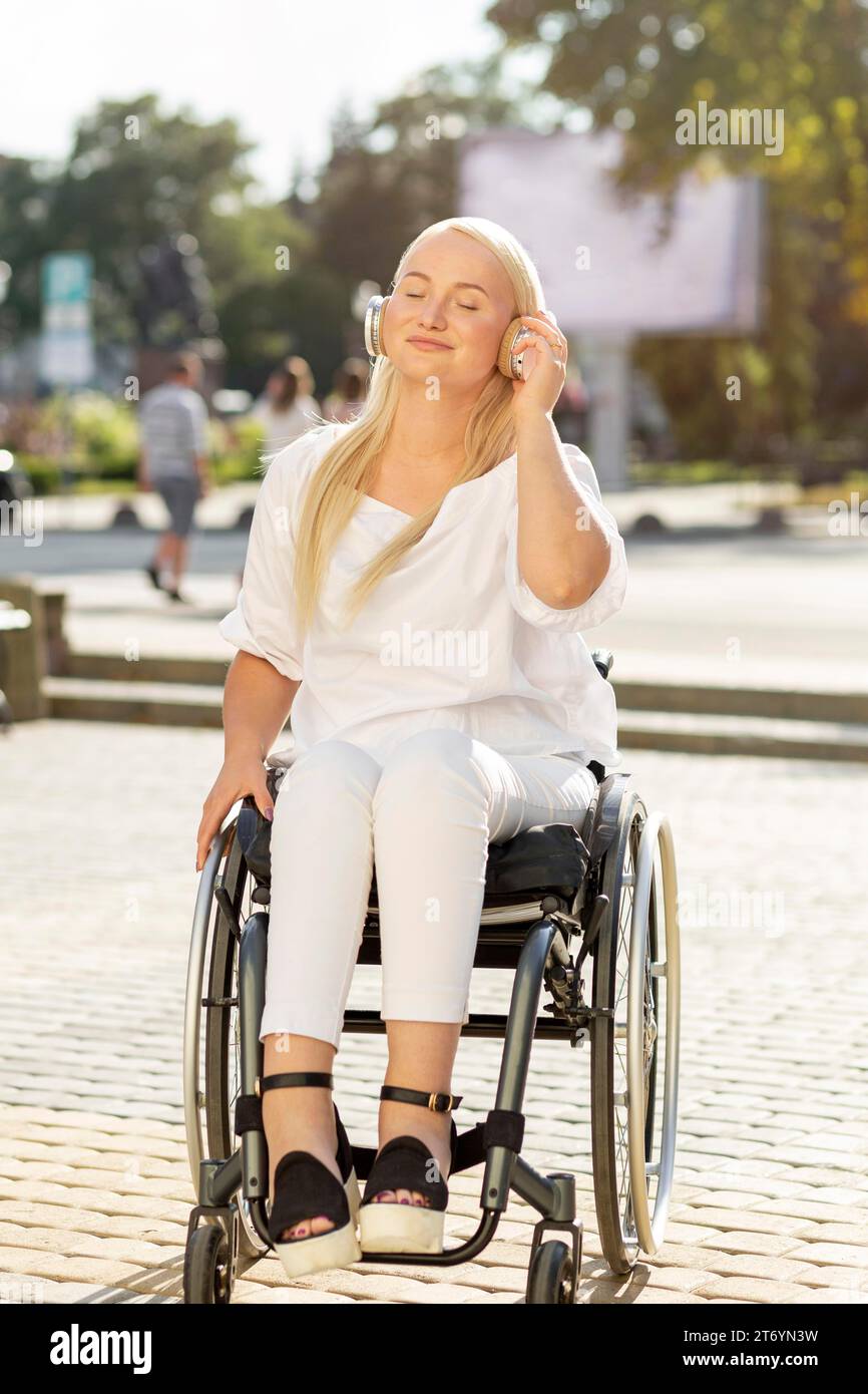 Smiley woman wheelchair listening music headphones outside Stock Photo ...