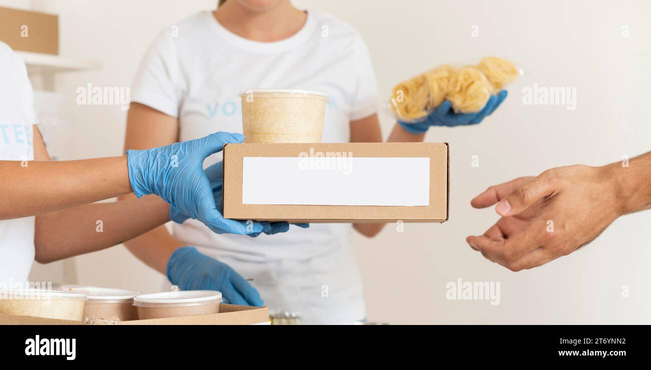 Volunteers with gloves handing out boxes with food donation Stock Photo ...