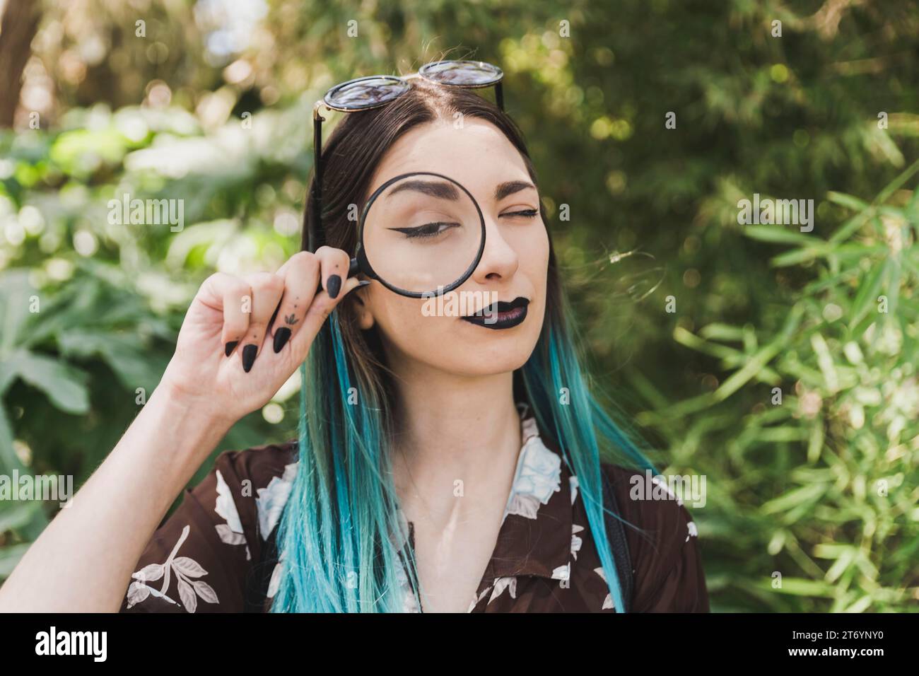 Young woman holding magnifying glass one eye Stock Photo - Alamy