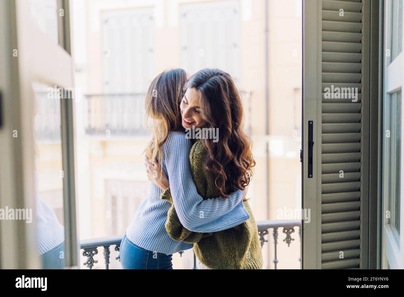 Women hugging balcony Stock Photo - Alamy