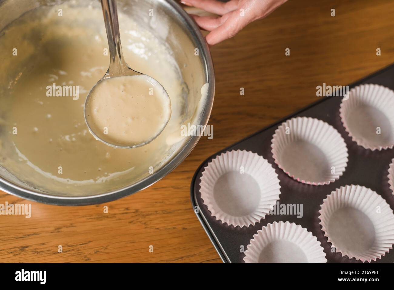 Close up hand pouring cake mix into baking muffins tray Stock Photo - Alamy