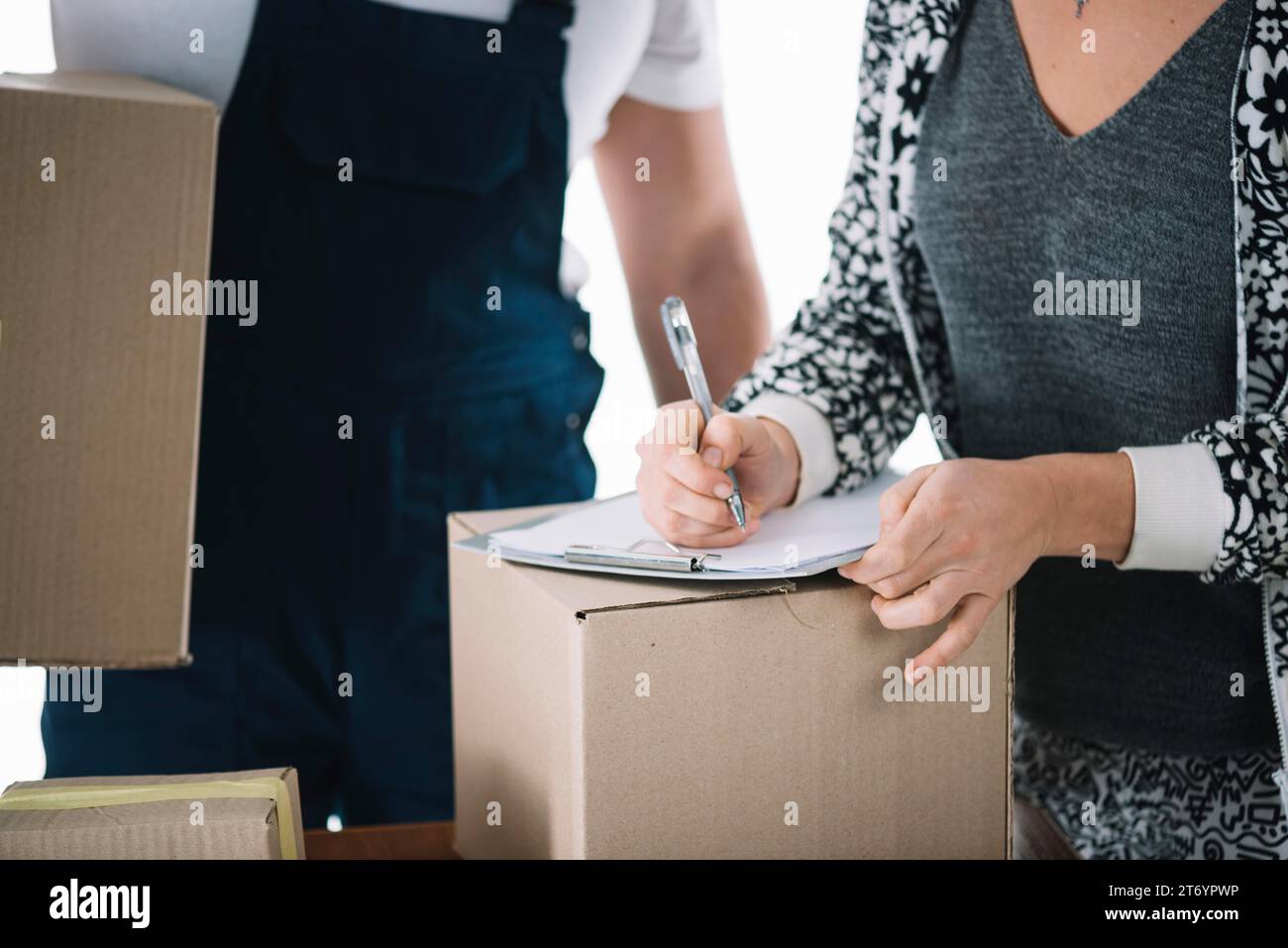 Crop woman signing carton box Stock Photo - Alamy