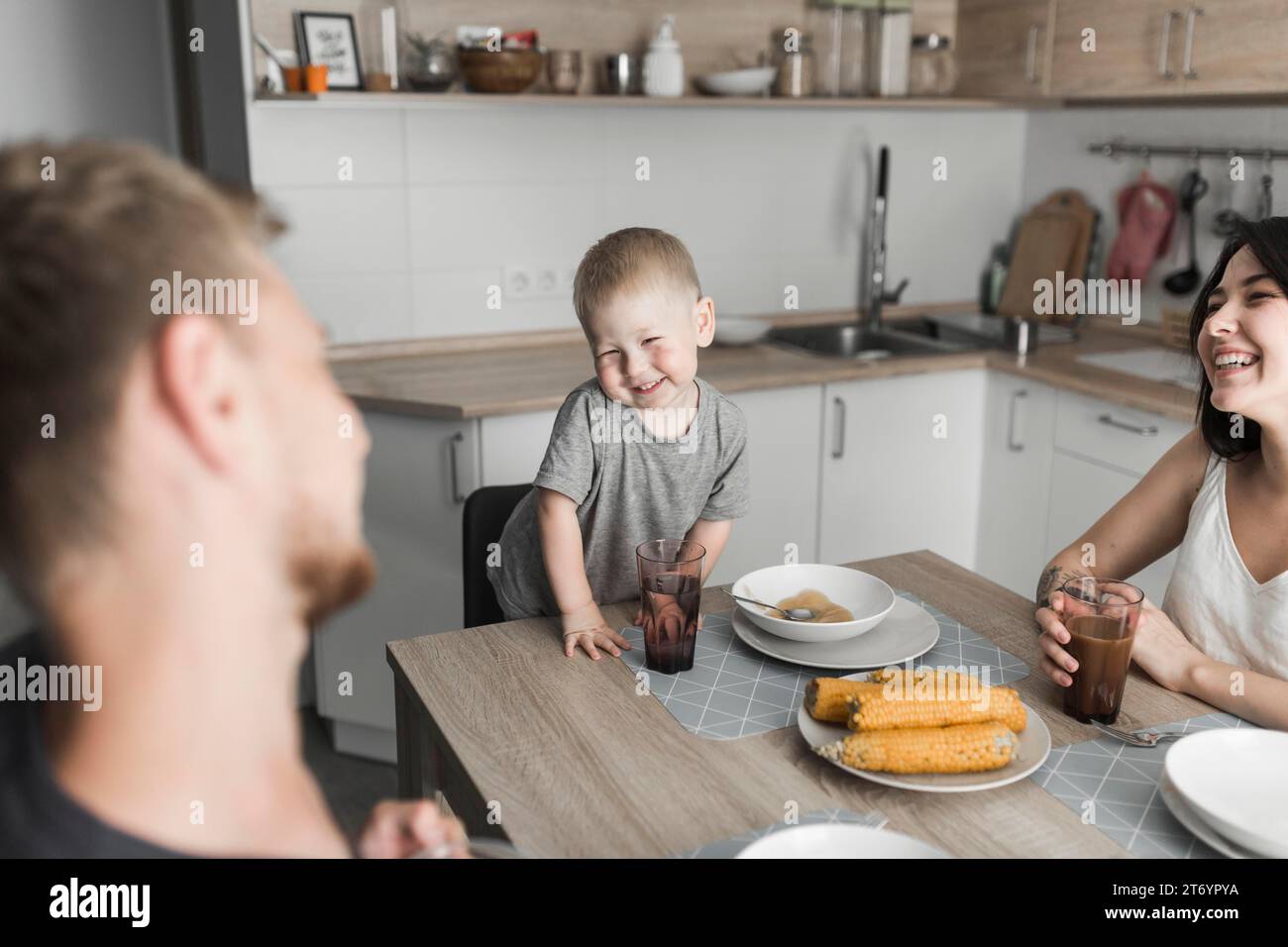 Cute boy enjoying breakfast with their parent kitchen Stock Photo - Alamy