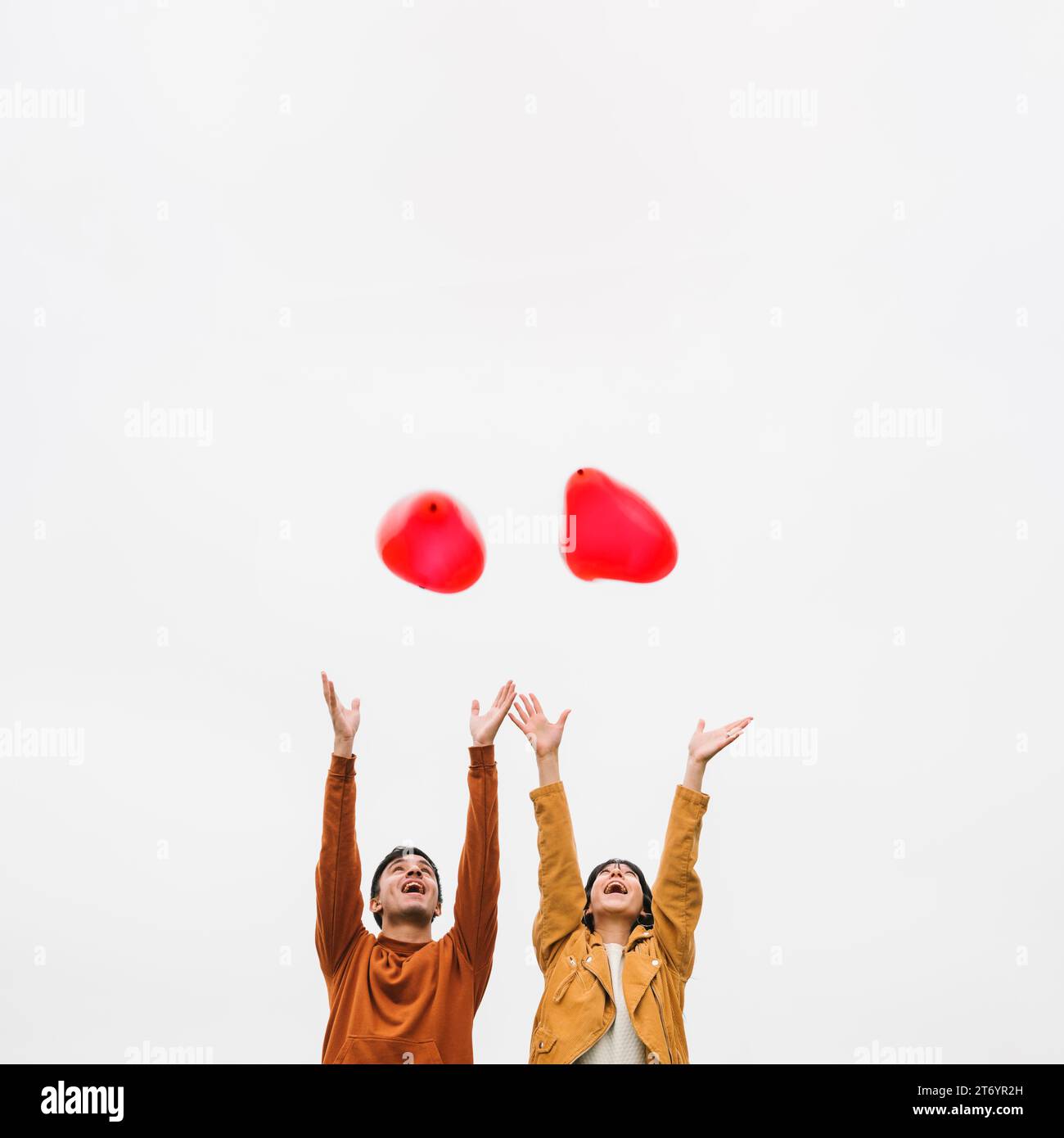 Excited young couple letting go balloons Stock Photo - Alamy