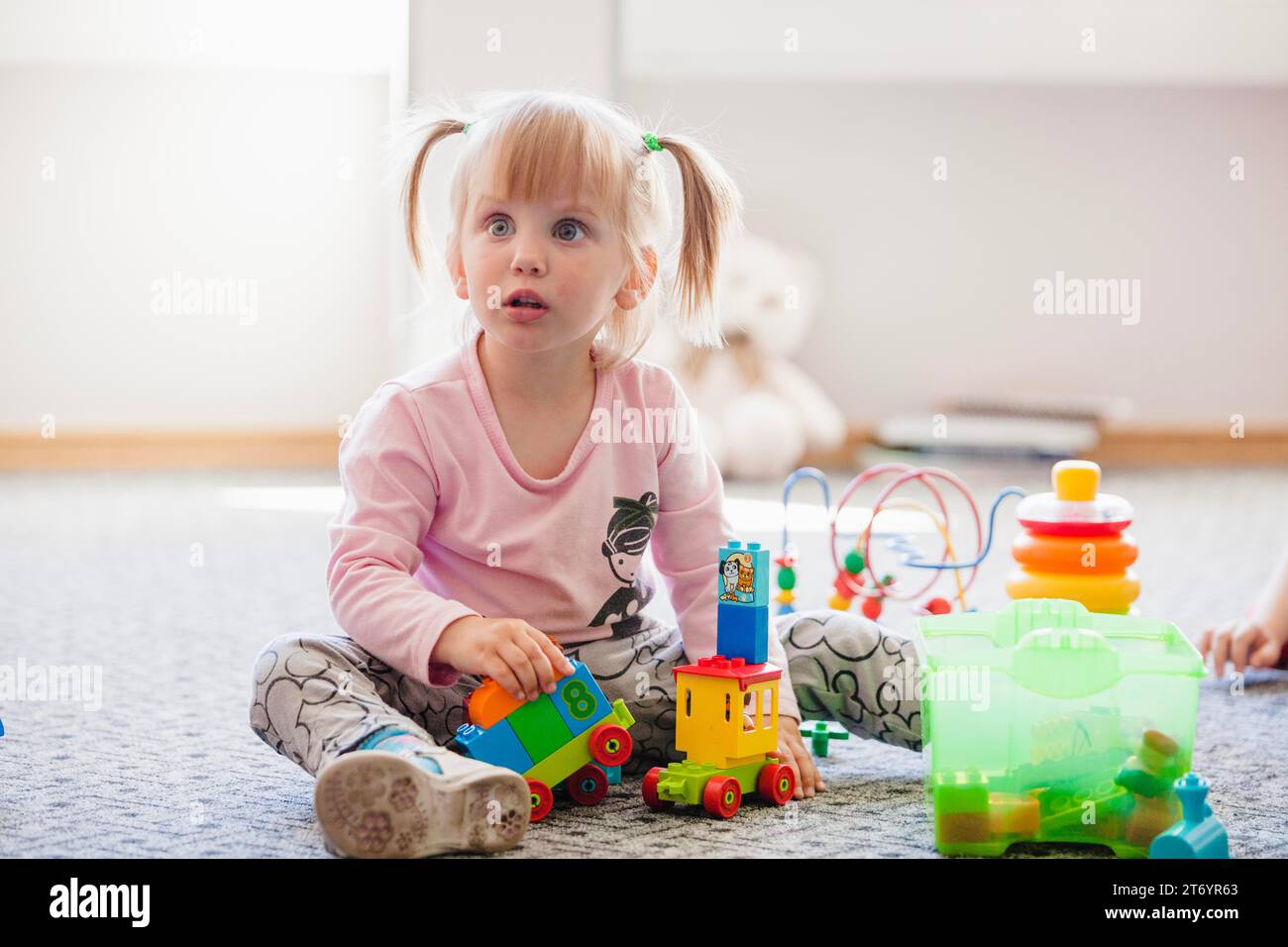 Distracted girl with toys looking away Stock Photo - Alamy