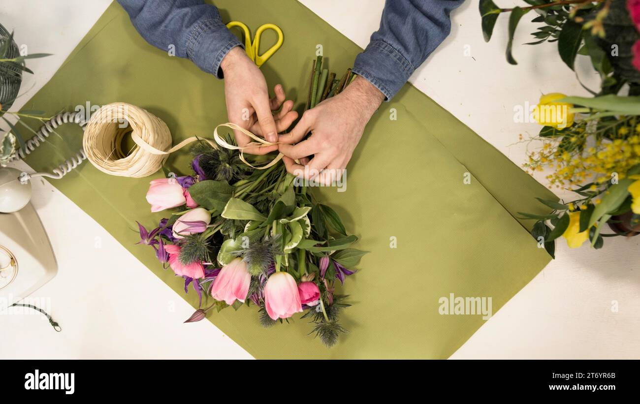 Elevated view male tourist tying flower bouquet with string green paper ...