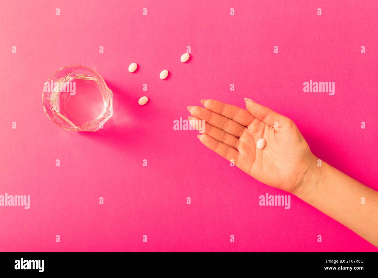 Elevated view female s hand taking medicine with water glass pink ...