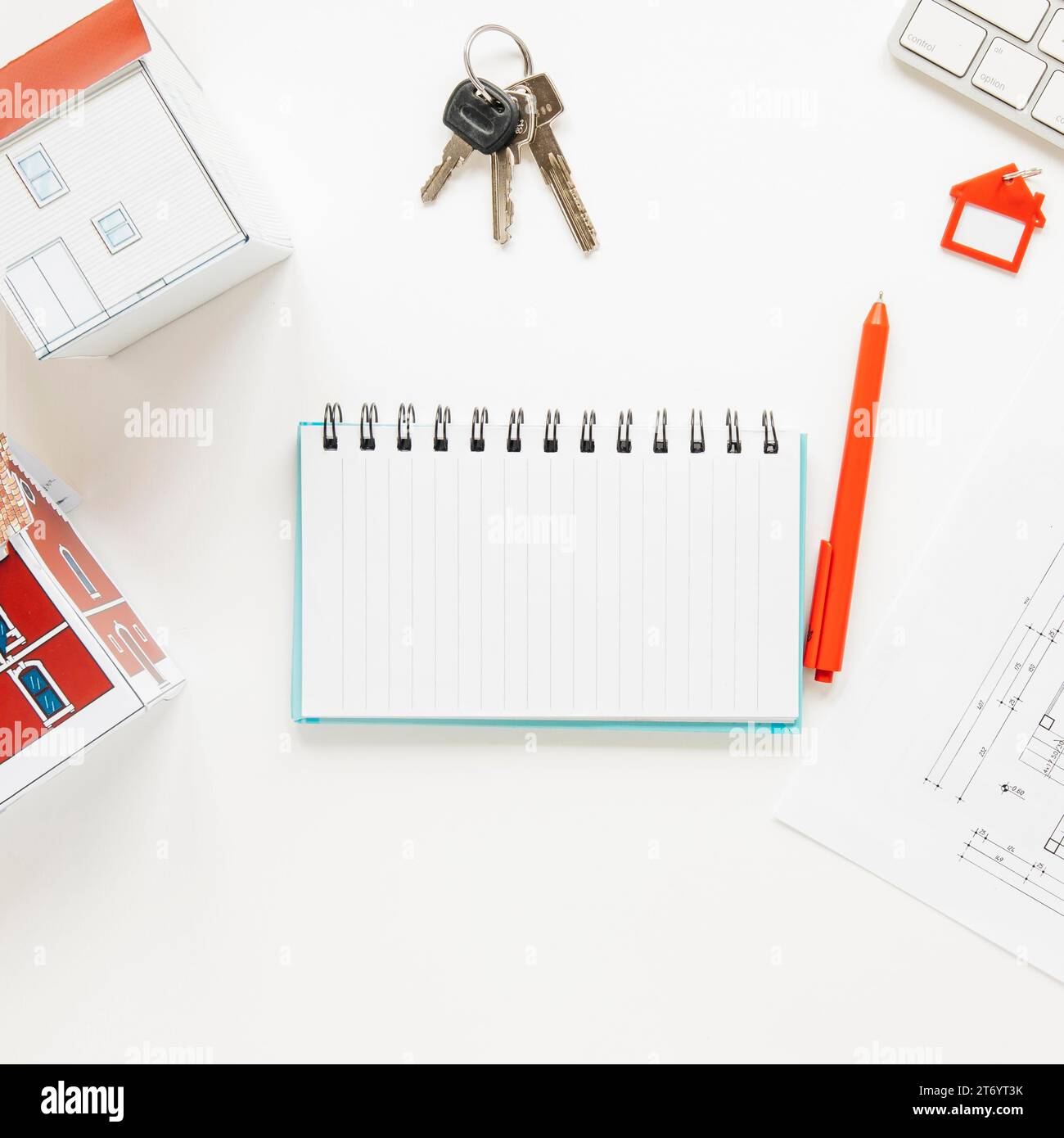 High angle view house model near spiral notepad with keys pen white ...