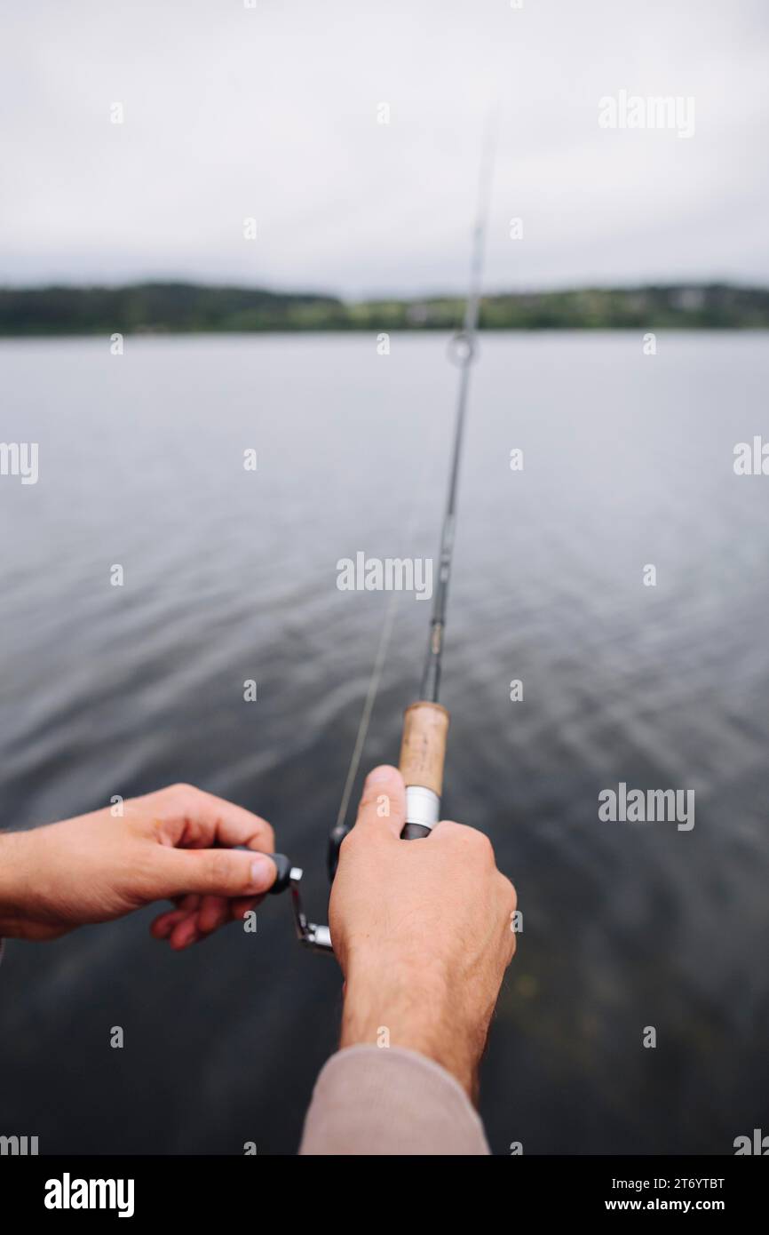 Man s hand holding fishing rod front lake Stock Photo - Alamy