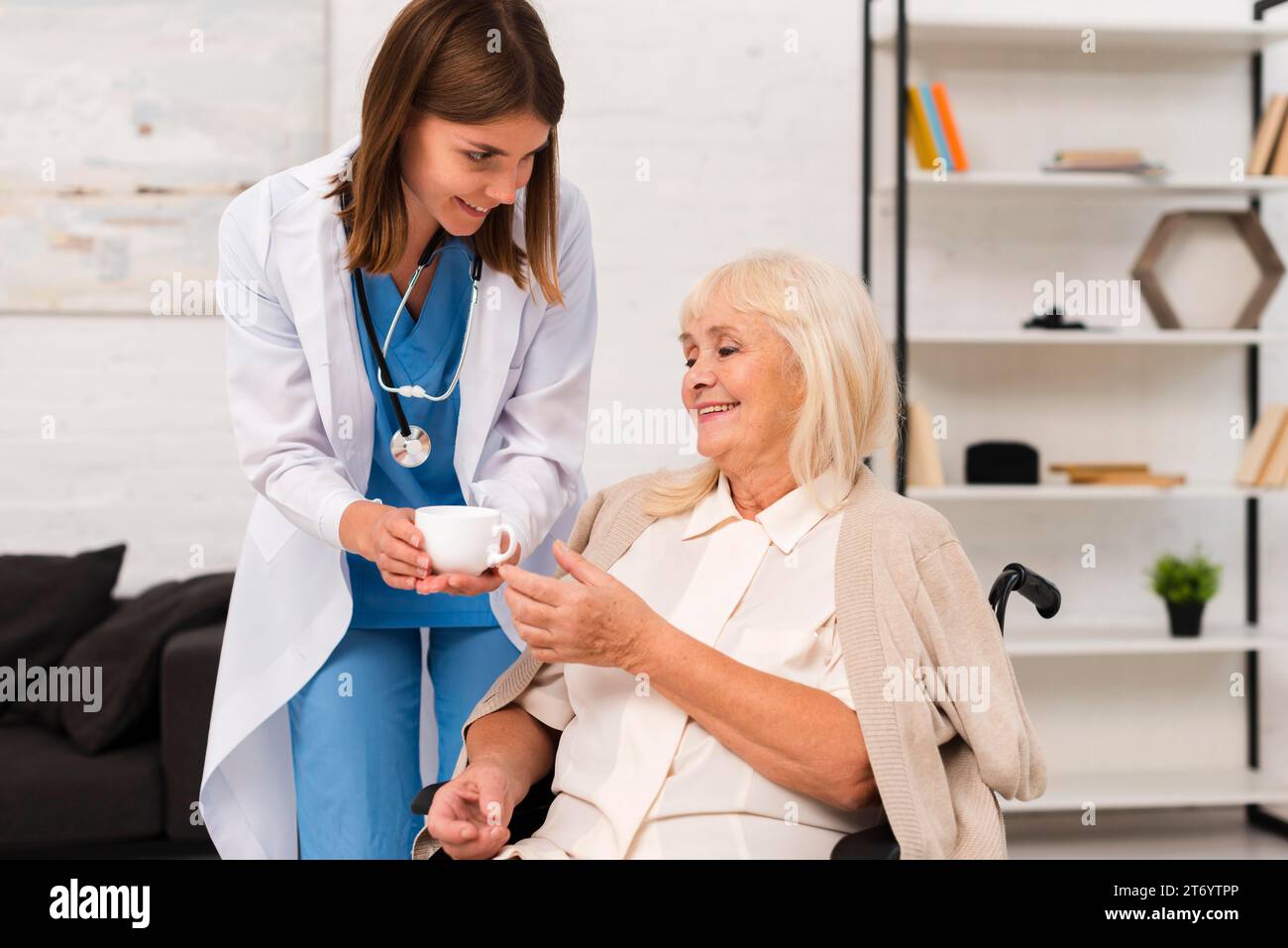 Nurse giving tea old woman Stock Photo - Alamy