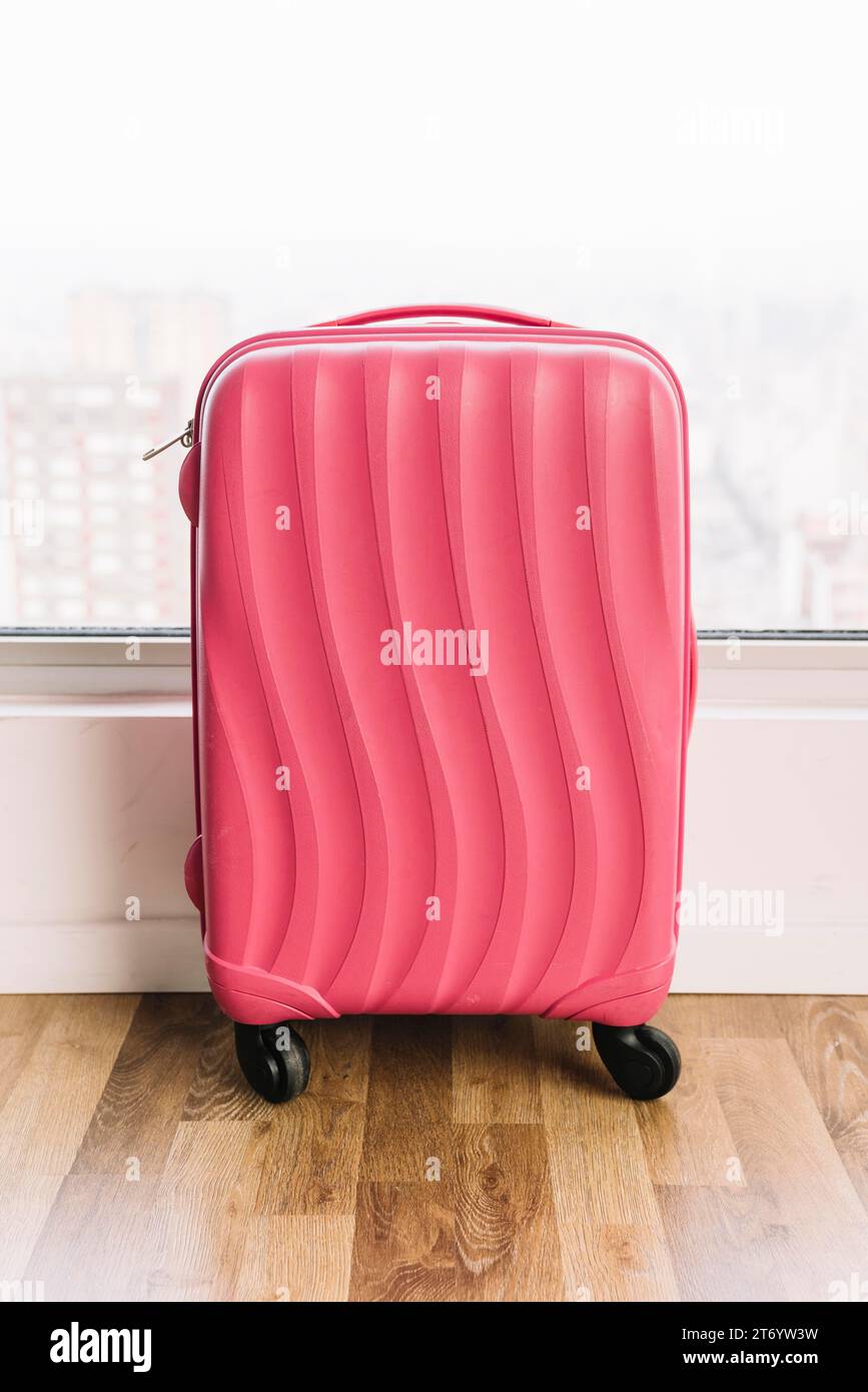 Pink travel plastic suitcase with wheels wooden floor Stock Photo - Alamy