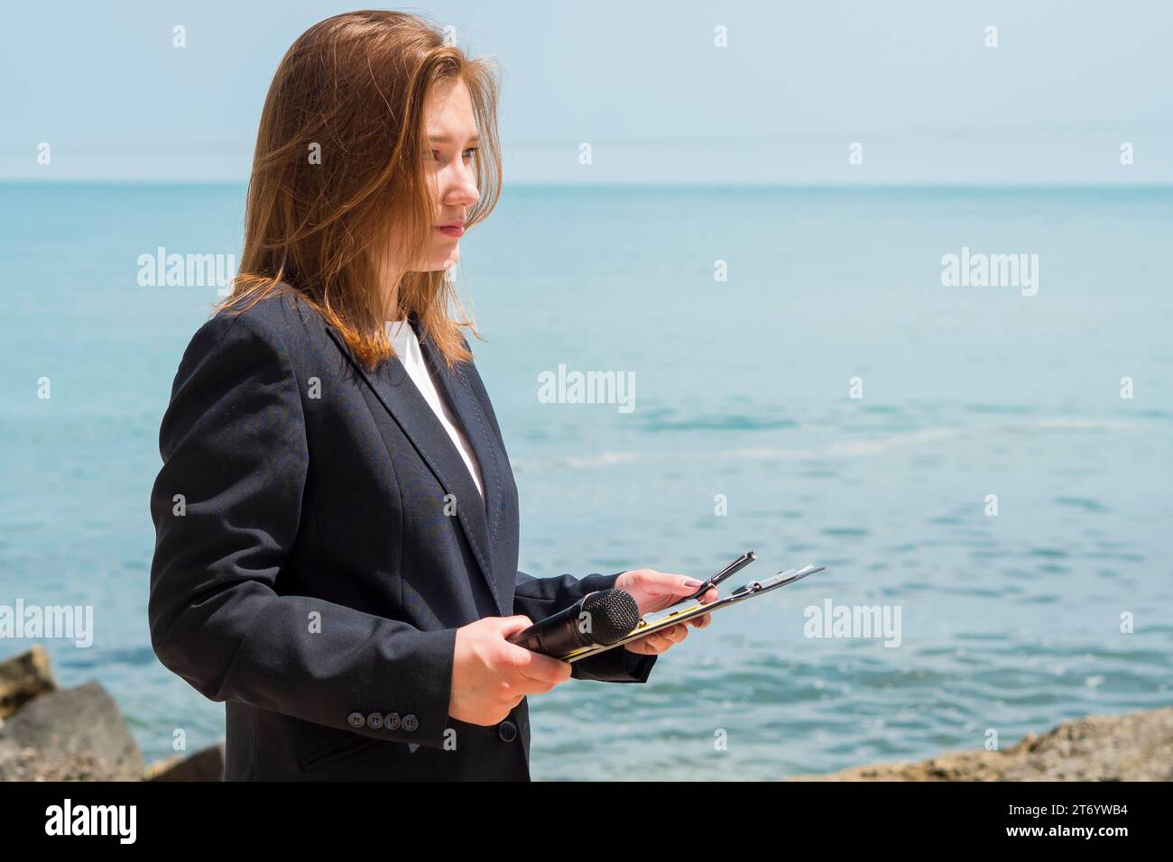 Reporter holding notepad by sea Stock Photo - Alamy