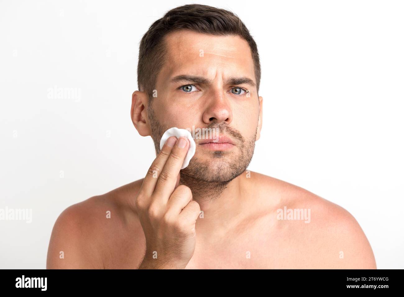 Serious young man cleaning his face against white background Stock ...