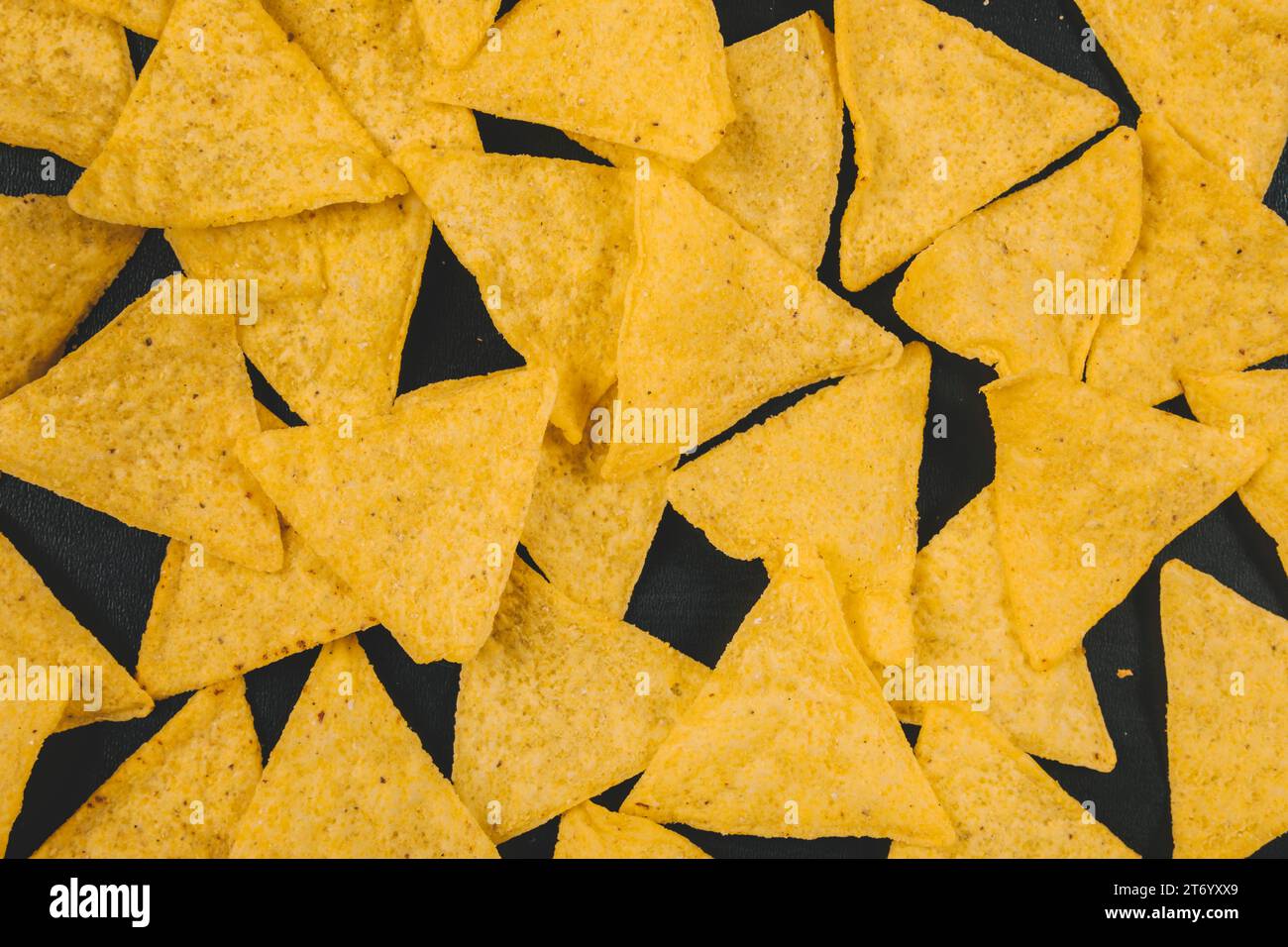 Yellow mexican nachos chips black background Stock Photo - Alamy