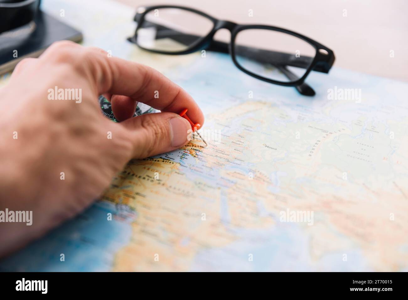 Close up person s hand holding push pin blur map Stock Photo - Alamy