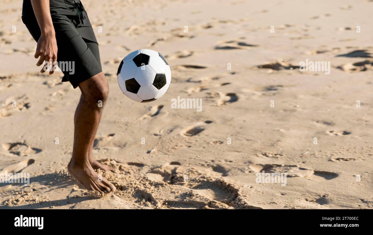 Crop man kicking ball sandy beach Stock Photo - Alamy