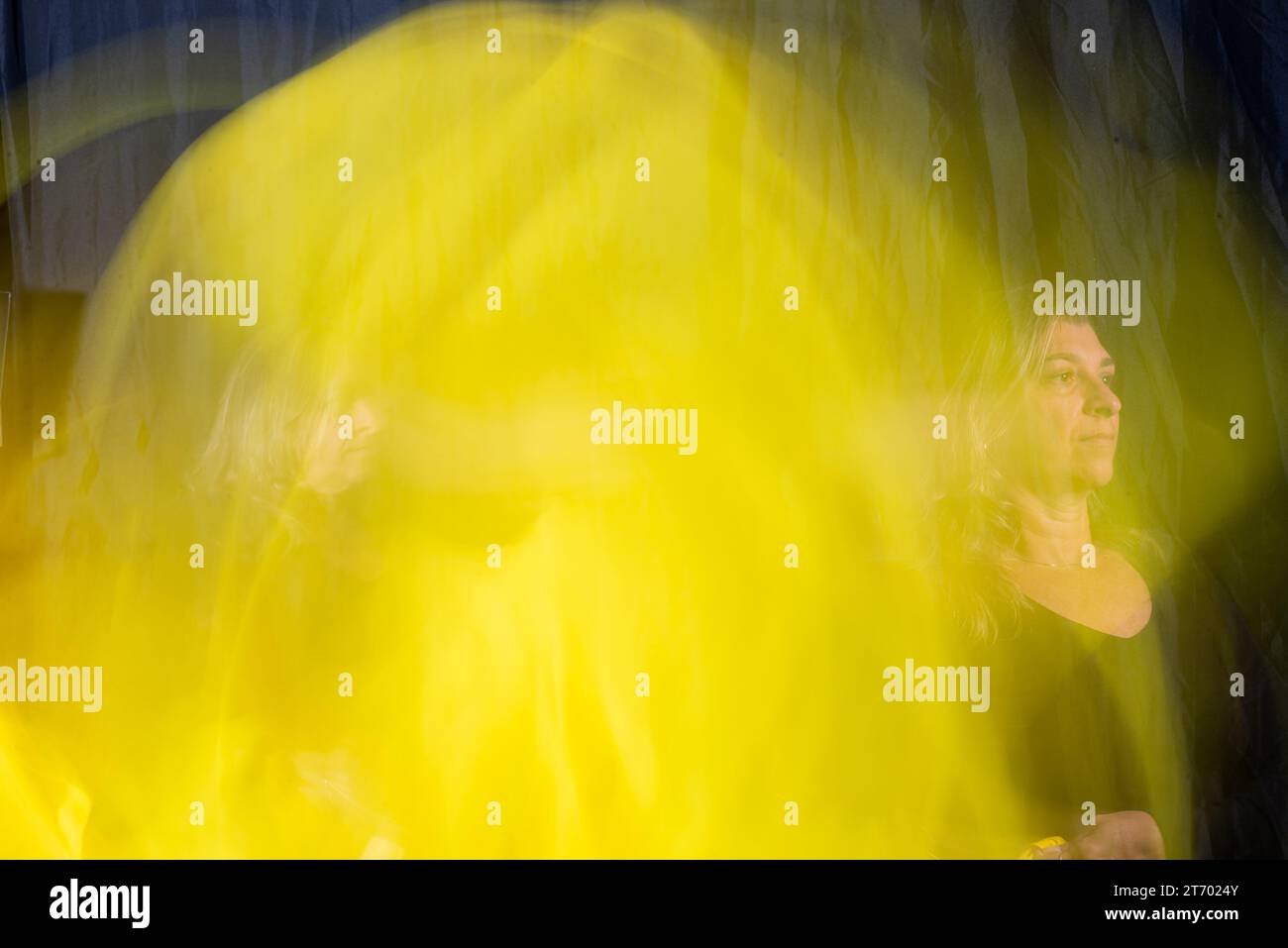 Woman actress dancer making fast movements with yellow cloth. Blurred ...