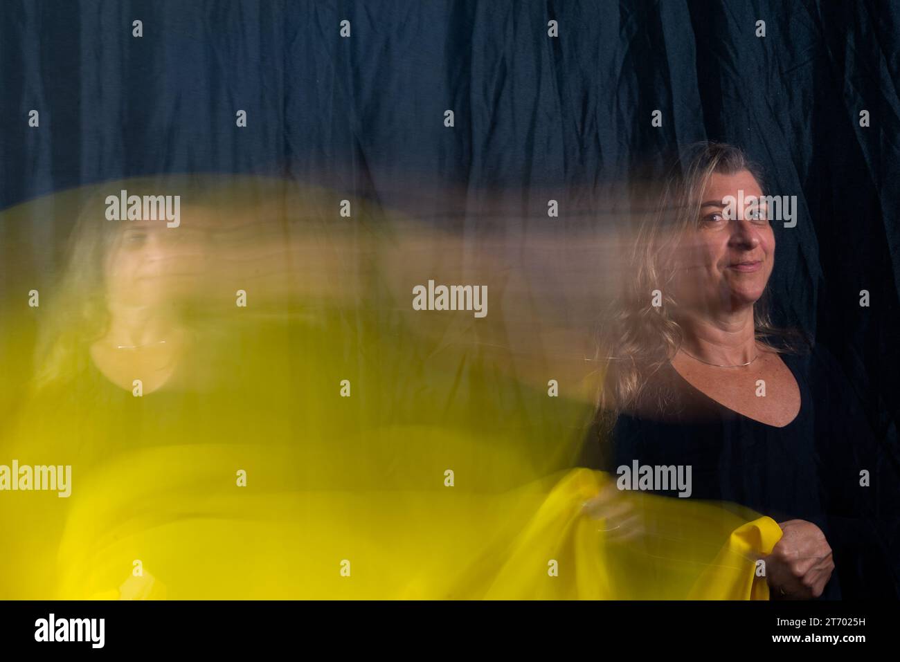Woman actress dancer making fast movements with yellow cloth. Blurred ...