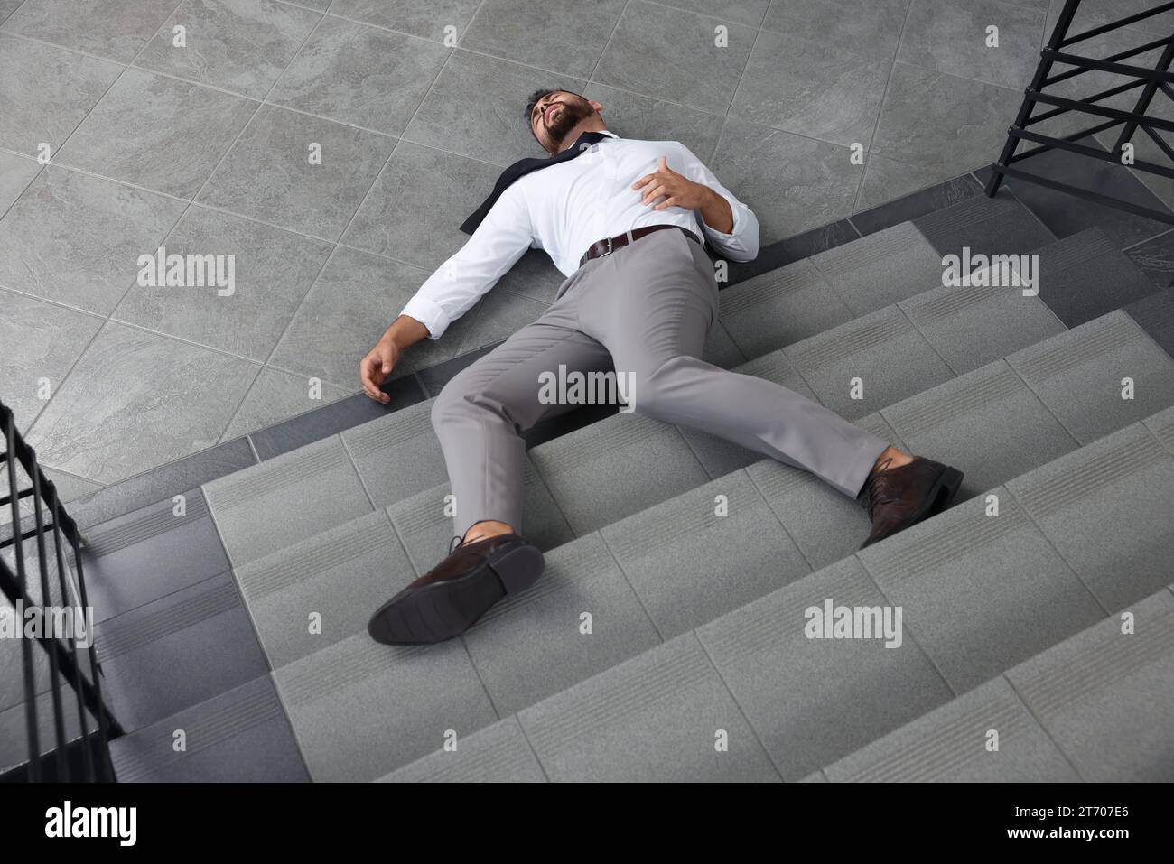 Unconscious man lying on floor after falling down stairs indoors Stock ...