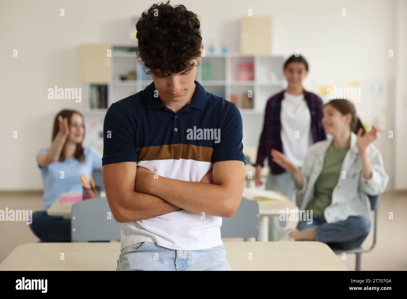 Teen problems. Lonely boy standing separately from other students in ...