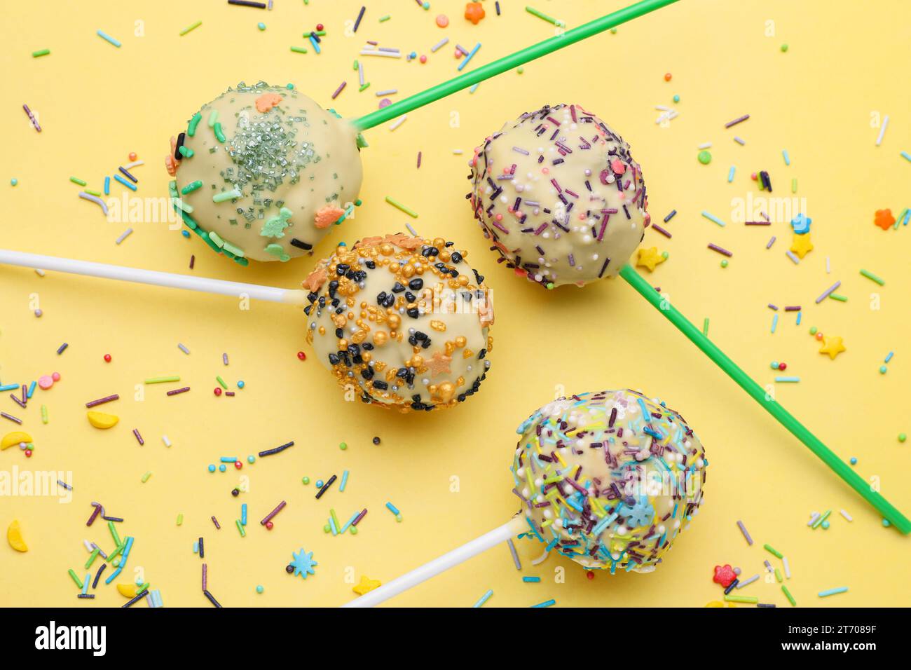 Delicious confectionery. Sweet cake pops and sprinkles on pale yellow ...