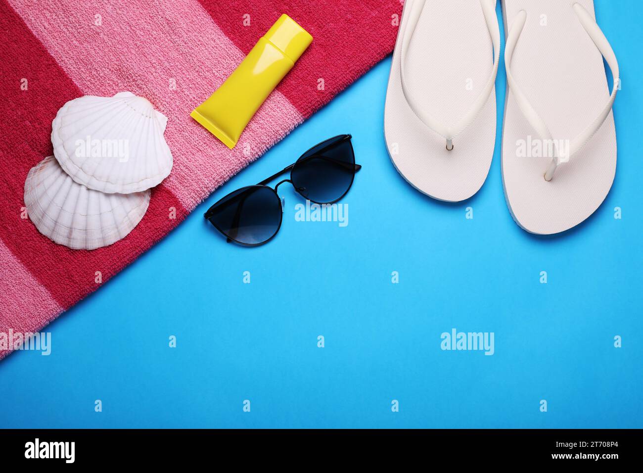 Flat lay composition with sunscreen and beach accessories on light blue ...