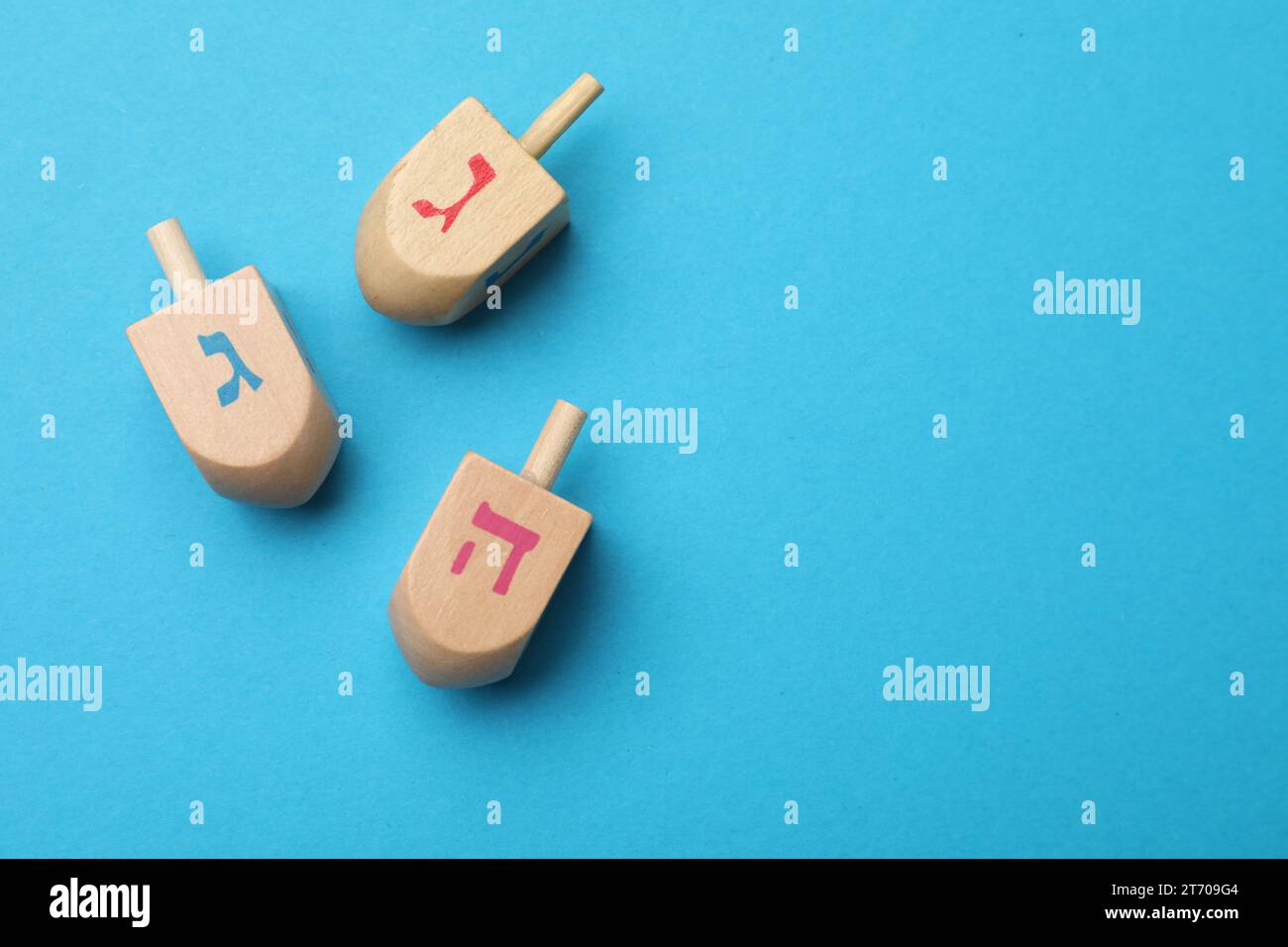Wooden dreidels on light blue background, flat lay with space for text ...