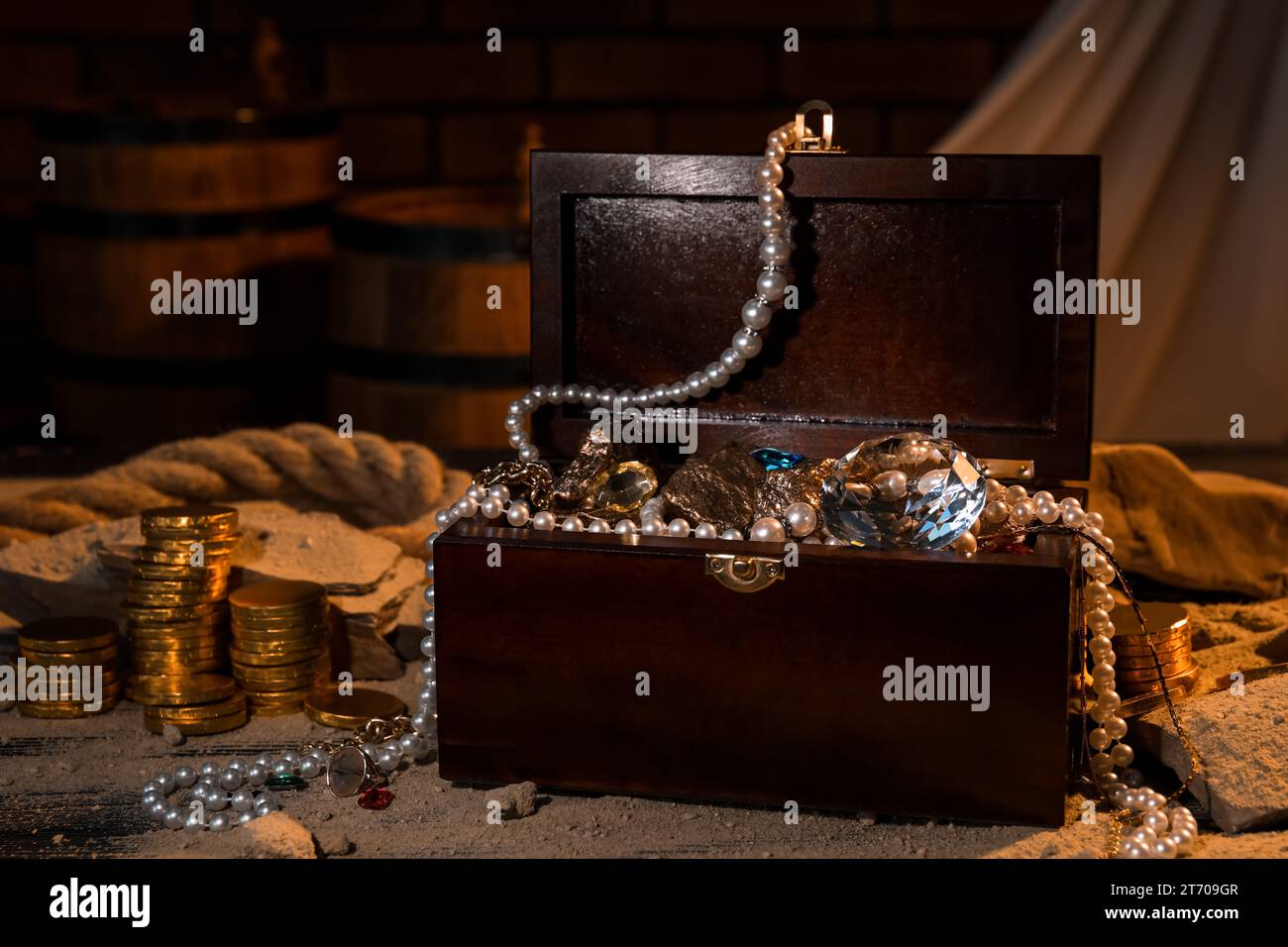 Chest with treasures, golden coins and scattered sand on table Stock ...
