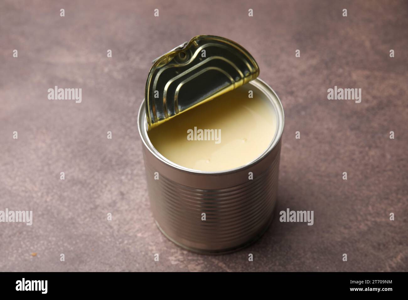 Open tin can with condensed milk on brown table Stock Photo - Alamy
