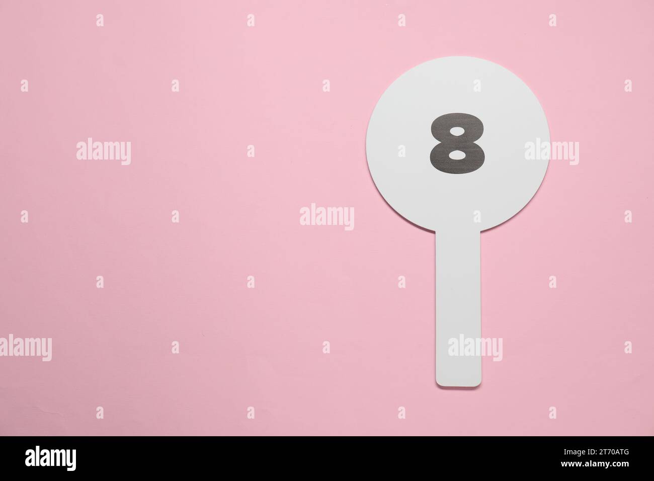 Auction paddle with number 8 on pink background, top view. Space for ...