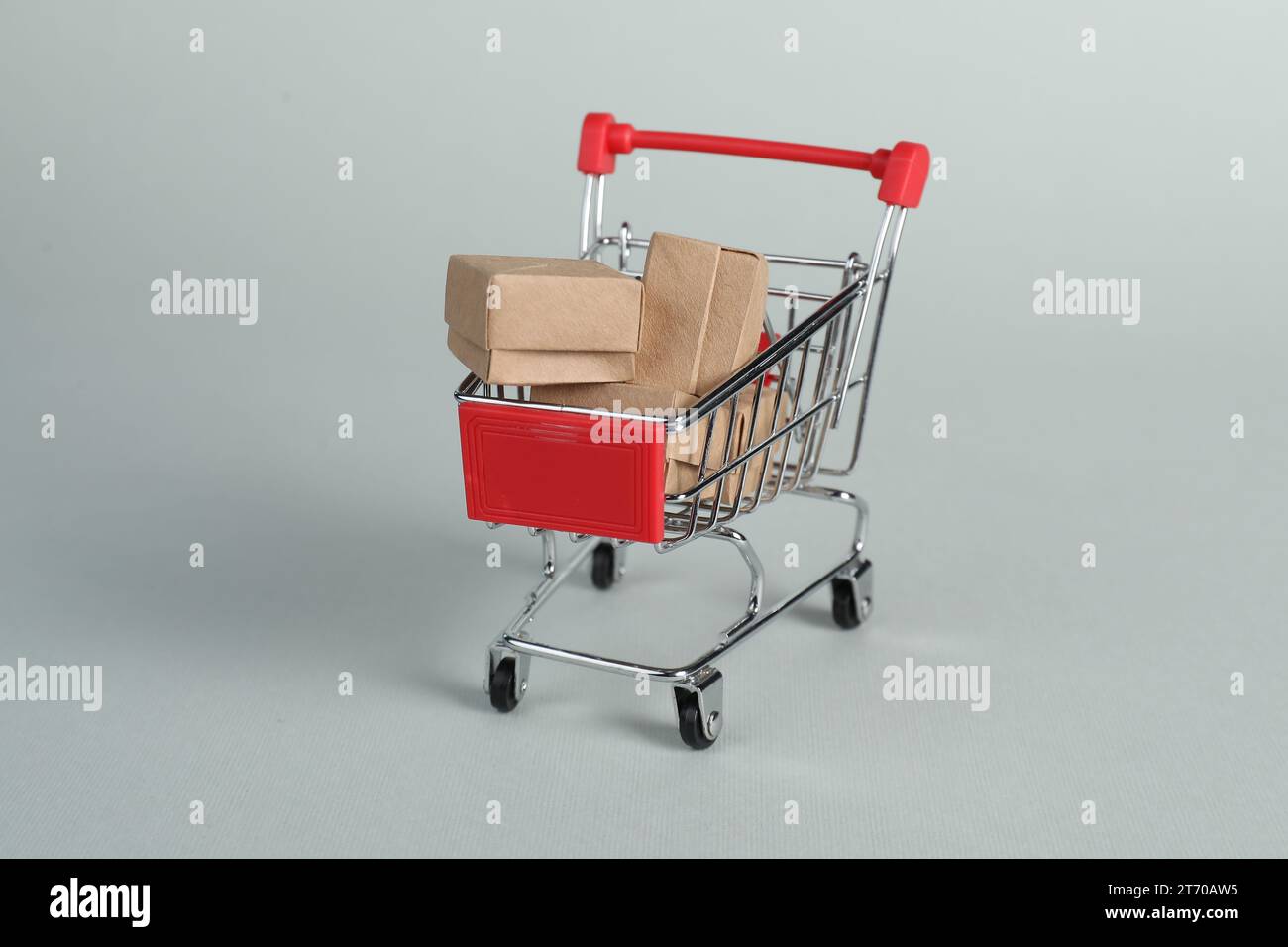 Small metal shopping cart with cardboard boxes on light background ...