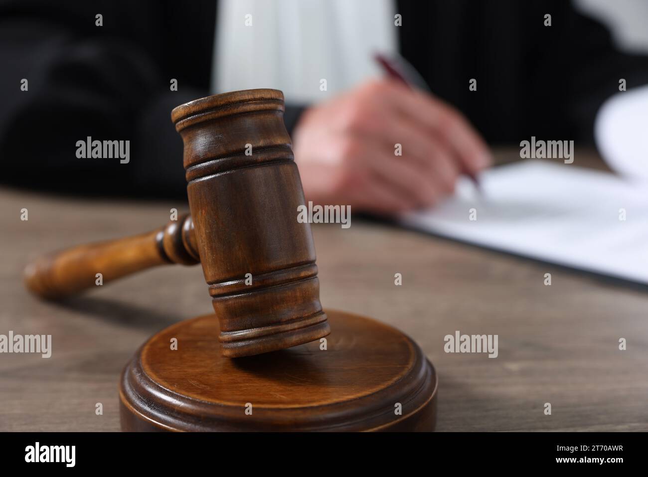 Judge with gavel writing in papers at wooden table, closeup Stock Photo ...