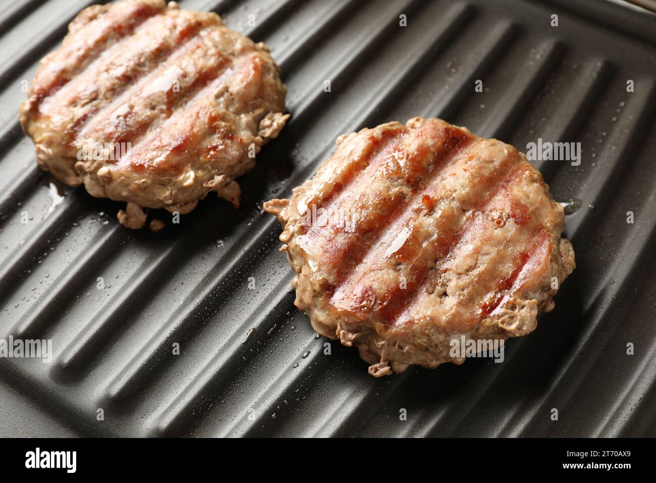 Delicious hamburger patties cooking on electric grill, closeup Stock ...